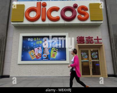 A pedestrian walks past a Dicos fastfood restaurant in Chongqing, China ...