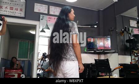 Chinese hairdresser Yan Xiaoping poses on a chair to show his long hair ...