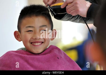 A Chinese kid has his hair cut at the barbers on Dragon Heads-raising ...