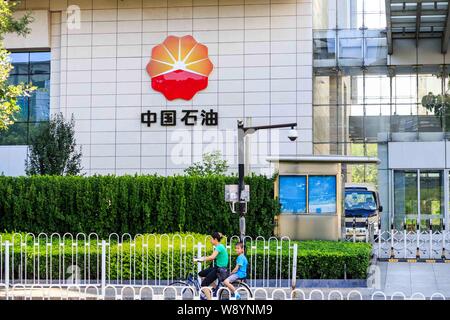 --FILE--Cyclists ride past the headquarters building of CNPC (China ...