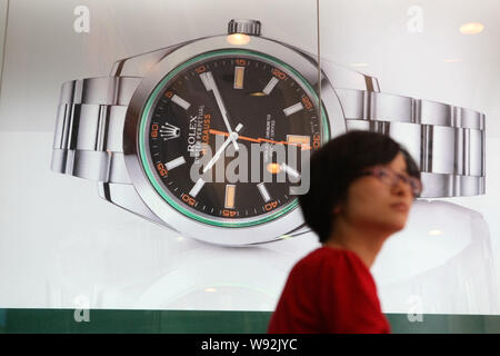 A pedestrian walks past an advertisement for Rolex watches in Shanghai ...