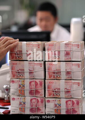 --FILE--Chinese clerks count RMB (renminbi) yuan banknotes at a branch ...