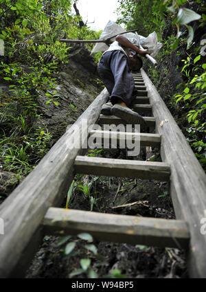 Local Chinese villagers climb the sky ladder on the cliff of a mountain ...