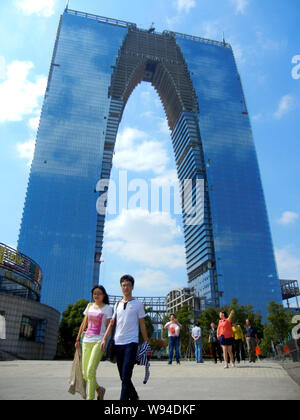Tourists walk past the pants-shaped skyscraper, Gate of the Orient ...