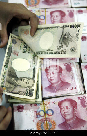 A Chinese clerk counts Japanese yen bills over RMB (renminbi) yuan ...
