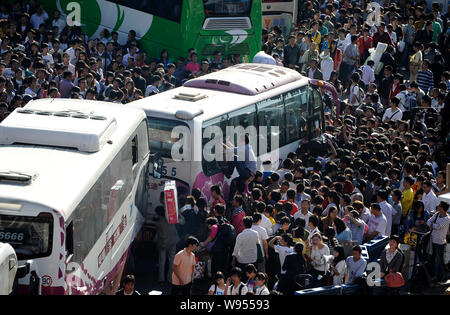Chinese travelers crowd around buses at a long-distance bus station ...