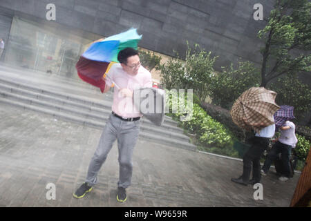 Pedestrians brave strong wind and heavy rain caused by Typhoon Haikui ...