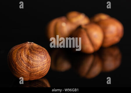 Lot of whole ripe brown hazelnut in dark ceramic bowl in tiny wooden ...