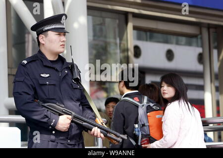 An armed Chinese policeman stands guard at the Shanghai Railway Station ...