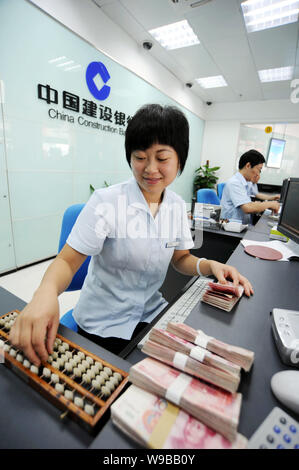 A Chinese bank clerk counts RMB banknotes at the Lujiazui subbranch of ...