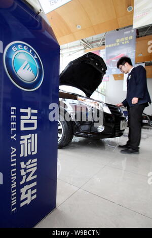 A Chinese employee checks a Geely car at a Geely dealership in Shanghai ...