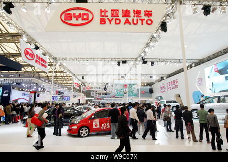 FILE - Visitors look at cars at the BYD booth during the China Auto ...