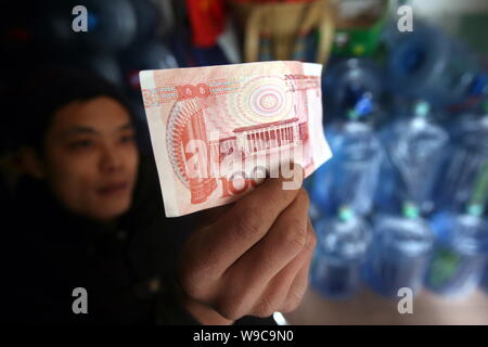 A Chinese man shows a fake RMB (renminbi) 100 yuan (US$14.50) bank note ...