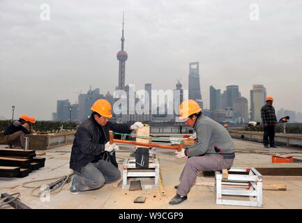 Chinese construction workers labor at the jobsite of the Bund promenade ...