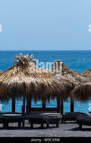 Sun loungers on the black volcanic beach of Kamari in Santorini ...
