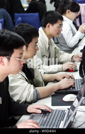 Chinese IT engineers work on their laptop computers at a cartoon ...