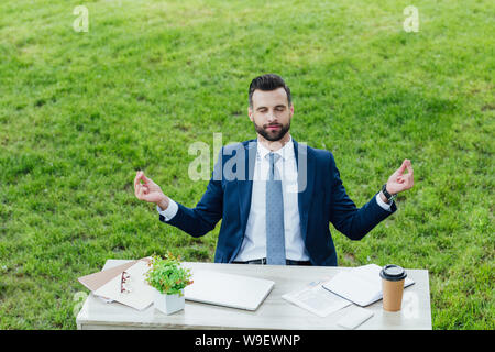 Handsome young man meditating at table in kitchen Stock Photo - Alamy