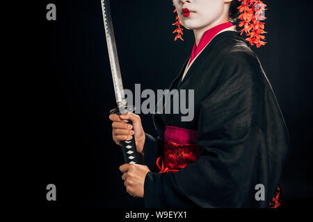 side view of geisha in black kimono holding katana in smoke on black ...