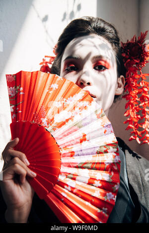 Portrait of young geisha holding fan, studio shot Stock Photo - Alamy