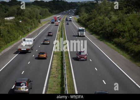 M4 motorway with cars and lorries in Wales with overhead gantry showing ...
