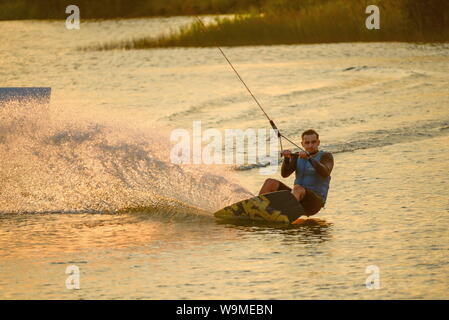 Wakeboarder making tricks. Low angle shot of man wakeboarding on a lake ...
