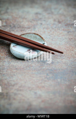 Wooden chopsticks and chopstick rest on dark stone background. Top view ...