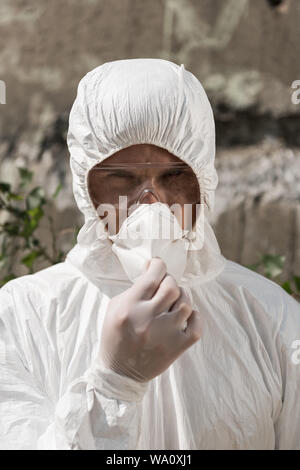 ecologist in protective costume and respirator touching tree in forest ...