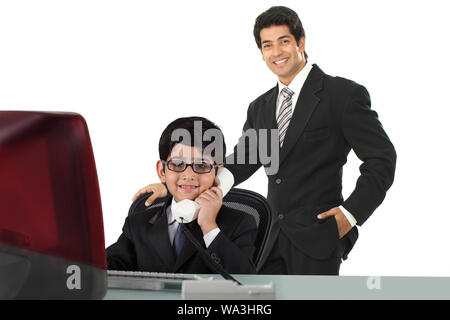 Boy imitating as a businessman and using a computer with his father ...
