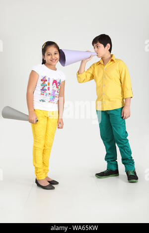 Boy shouting into friend,s ear through megaphone Stock Photo - Alamy