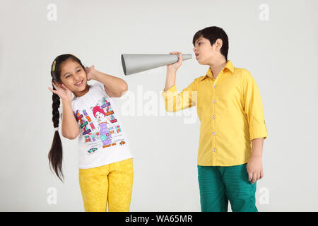 Girl shouting into friend ear through megaphone Stock Photo - Alamy