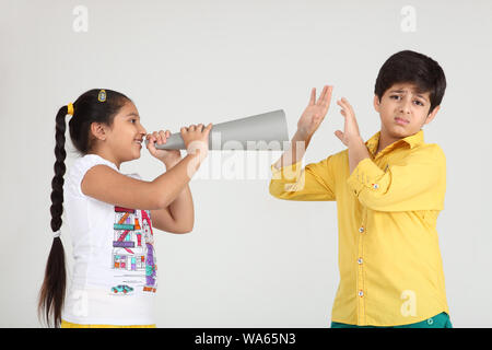 Girl shouting into friend ear through megaphone Stock Photo - Alamy