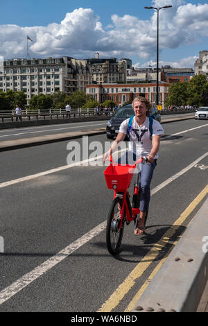 A man cycling across London Bridge during rush hour, on a Transport for ...