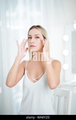 Woman in white dress applying perfume on her neck Stock Photo - Alamy