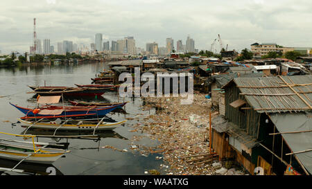 Manila slums on the background of a big city. Houses and boats of the ...