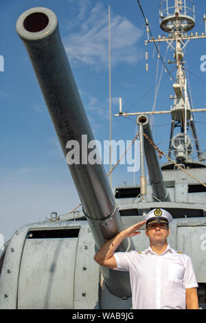 A navy officer standing under a ship's cannon and do salute.The captain ...
