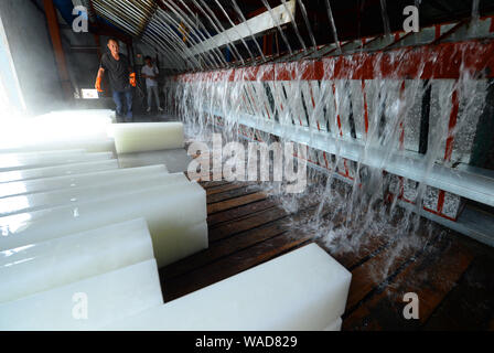 A Chinese worker manufactures ice blocks at a factory in Liuhe town ...