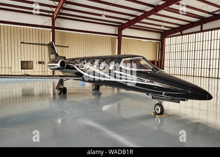 Private black 1970's vintage Lear Jet, parked in an airport hanger, at ...