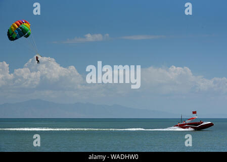 A tourist tries out flying paraglider above the Bosten Lake, one of the ...