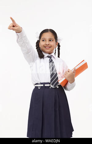 Happy indian school girl pointing advertising isolated on violet ...