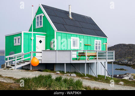 Typical Inuit wooden house painted blue and with sledges outside ...