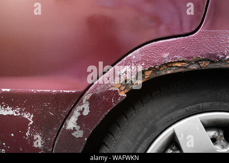 Rusty wing. Corrosion of the body of a red old car after winter ...