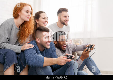 Group of millennials friends playing video games - Young people having ...