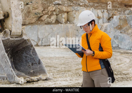 female geologist or a mining engineer writes something in a map-case ...