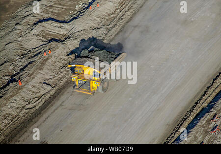 Giant trucks haul bitumen rich ore from mining operations to oil sands ...