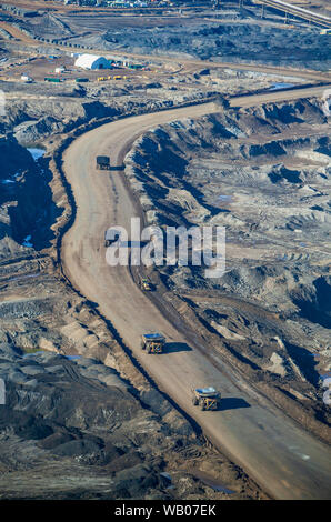 Giant trucks haul bitumen rich ore from mining operations to oil sands ...