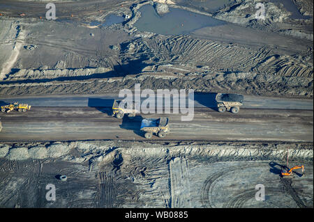 Giant trucks haul bitumen rich ore from mining operations to oil sands ...
