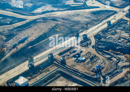 Giant trucks haul bitumen rich ore from mining operations to oil sands ...
