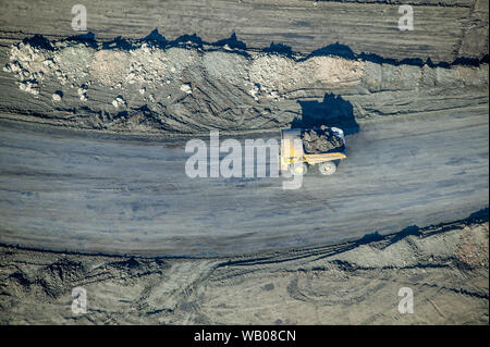 Giant trucks haul bitumen rich ore from mining operations to oil sands ...