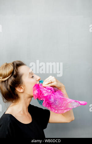 Portrait of a young woman suffocated of plastic bags, putting them into ...