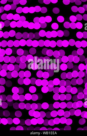 Unfocused abstract violet bokeh on black background. defocused and blurred many round light ...